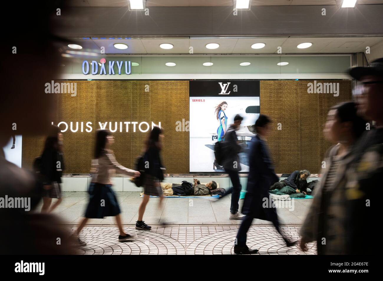 Commuters walking past homeless people sleeping outside the Odakyu ...