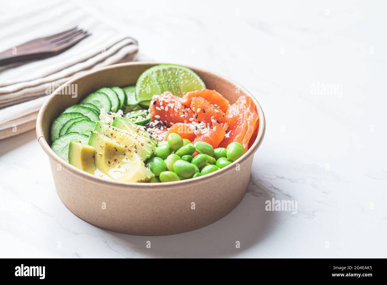 Poke bowl with rice, salmon, edamame beans, cucumber and avocado in a ...