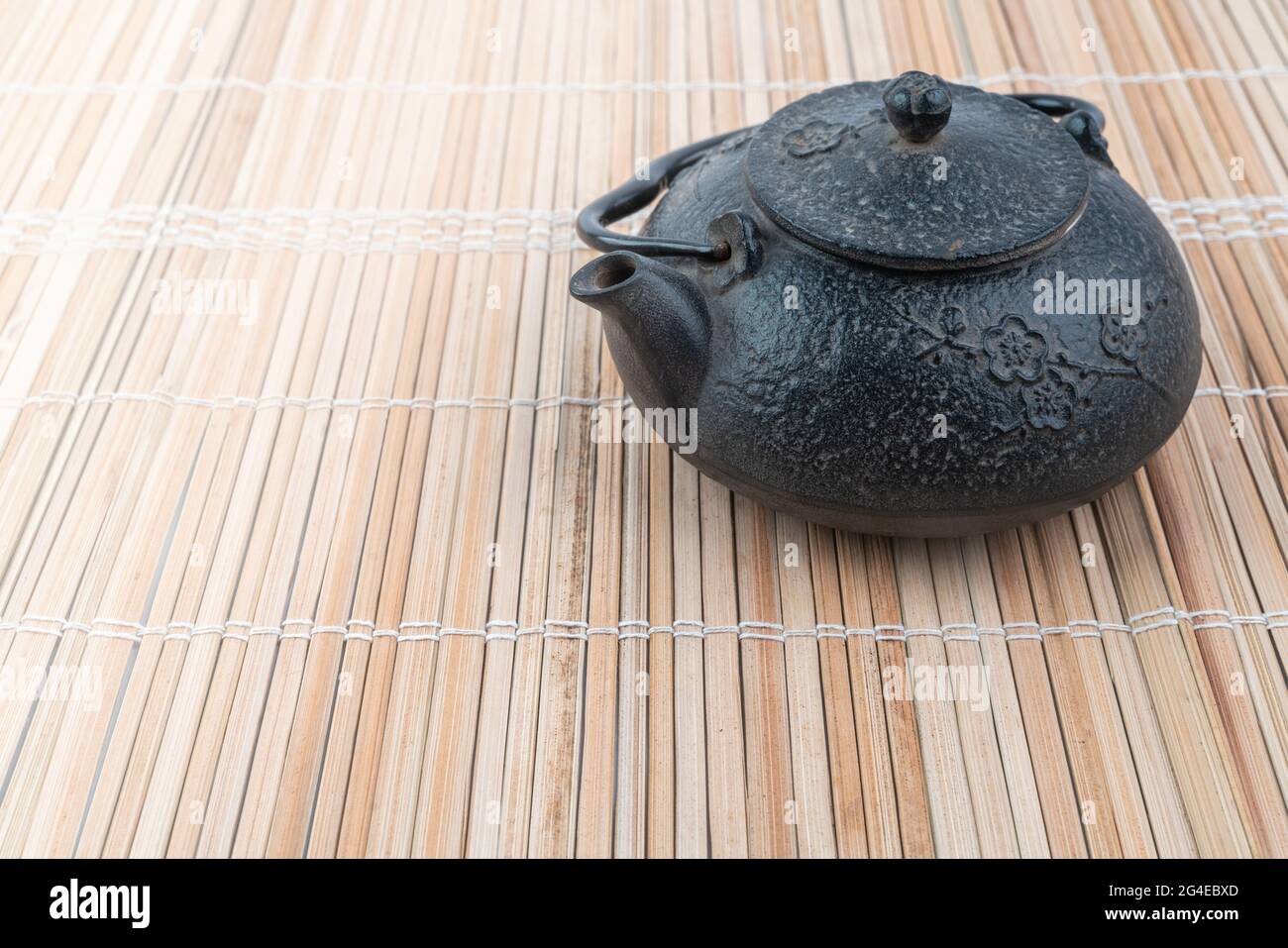 Vintage, black metal Japanese tea pot standing on a reed pad in a soft ...