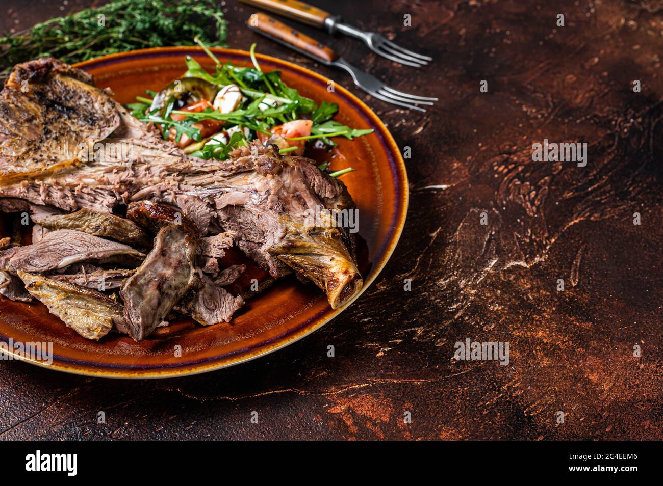 Grilled goat or lamb mutton shoulder meat in a rustic plate with salad ...