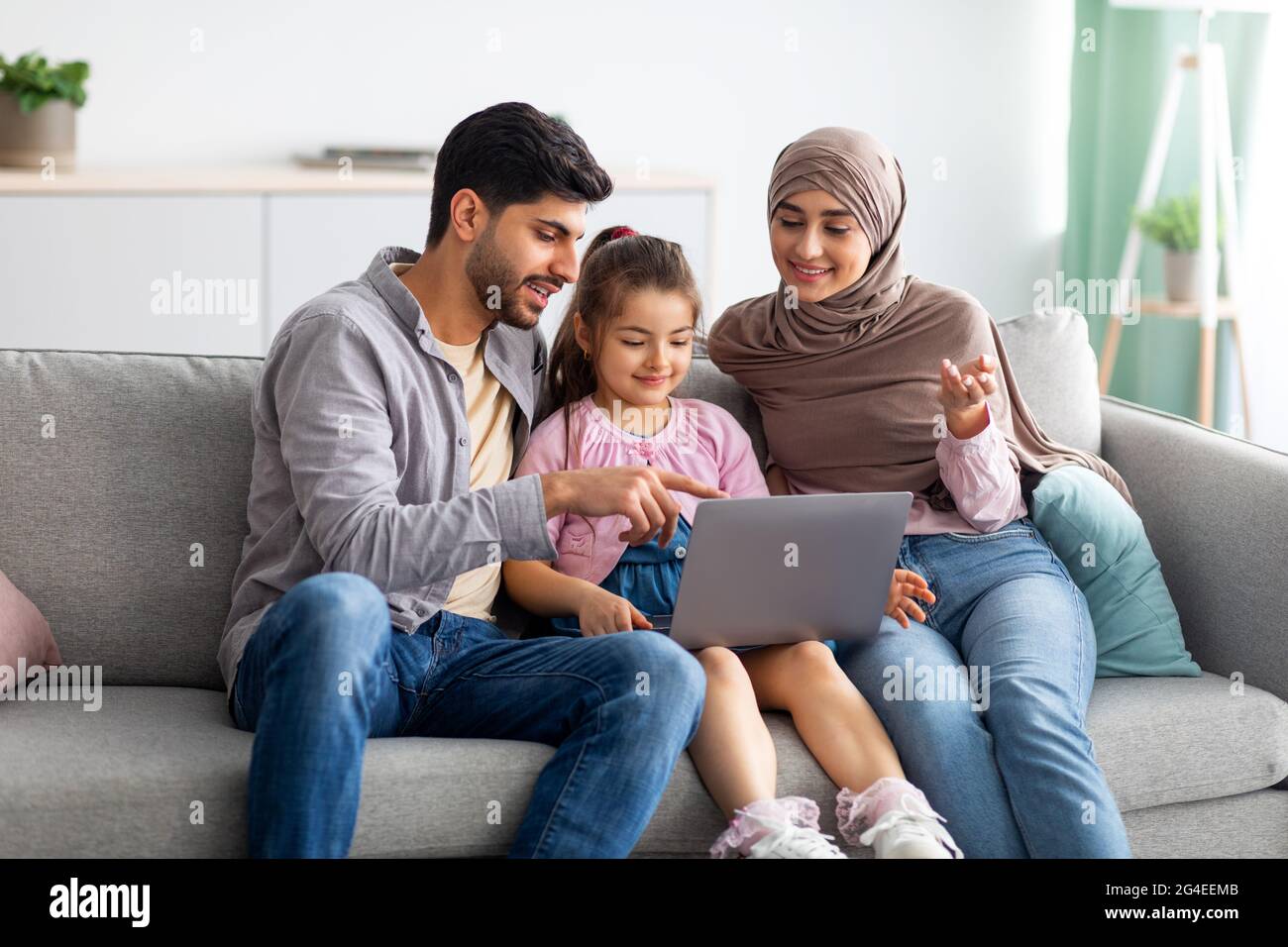 Modern muslim parents teaching their daughter using laptop computer ...