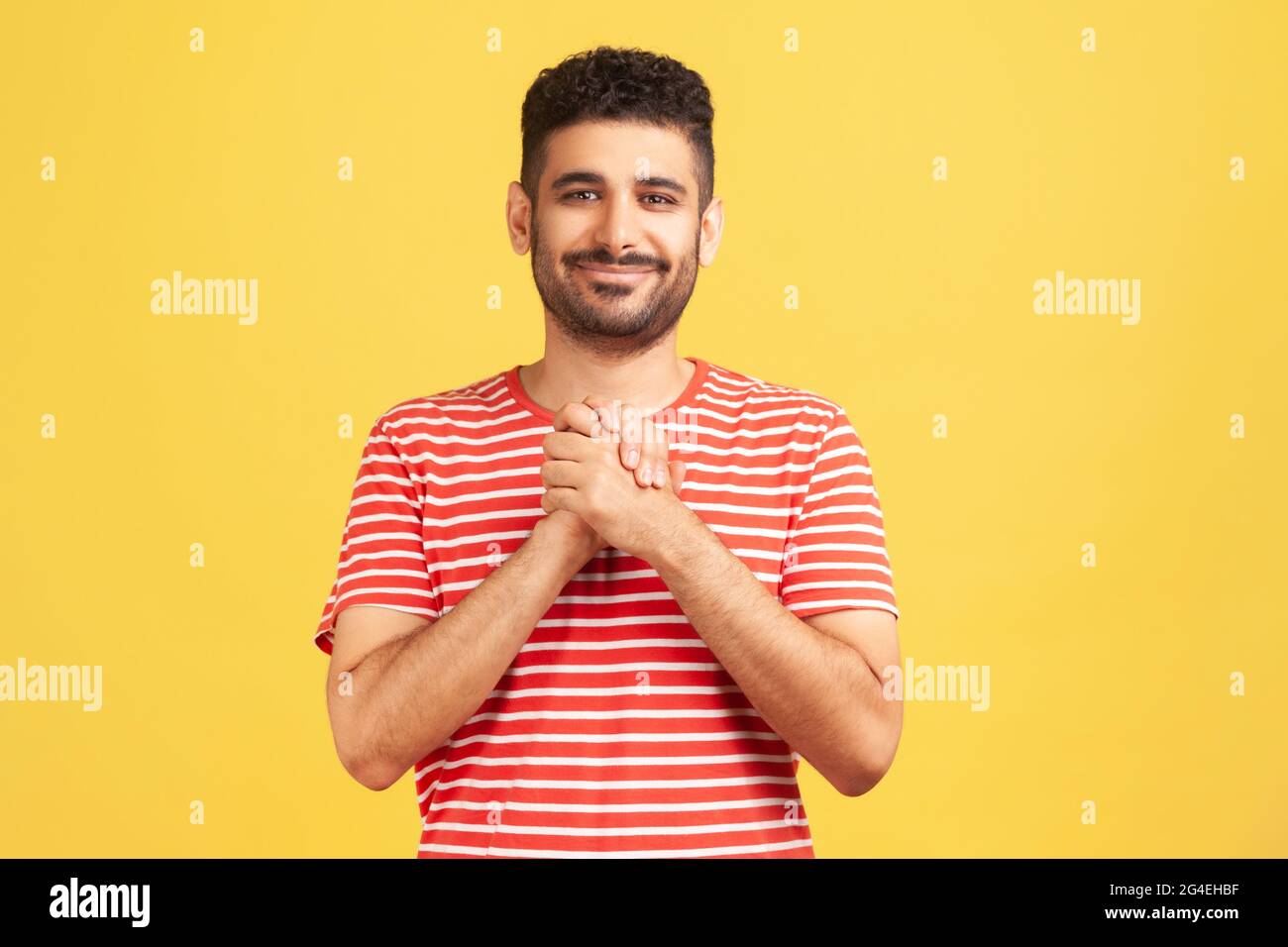 Happy positive man with beard in striped shirt pressing hands together ...