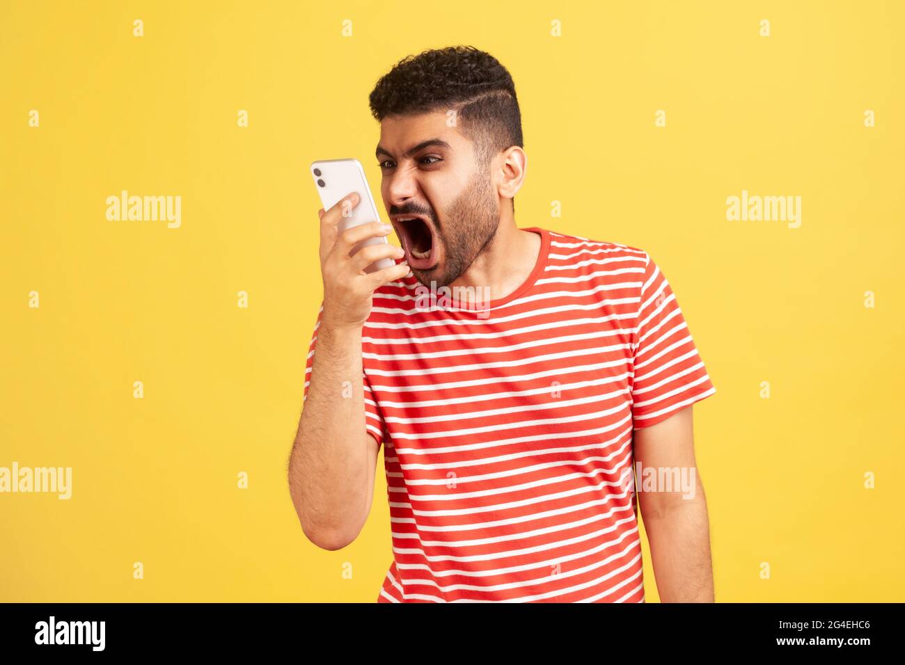 Angry mad man with beard in striped t-shirt loudly screaming talking ...