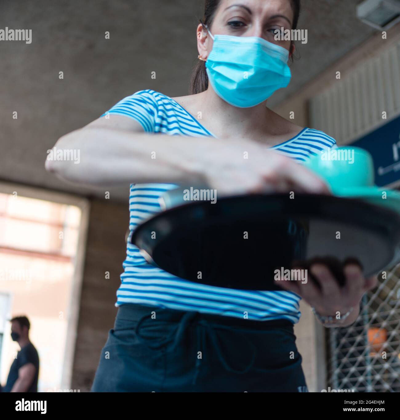 Low angle shot of a female waiter in a mask serving coffee Stock Photo ...