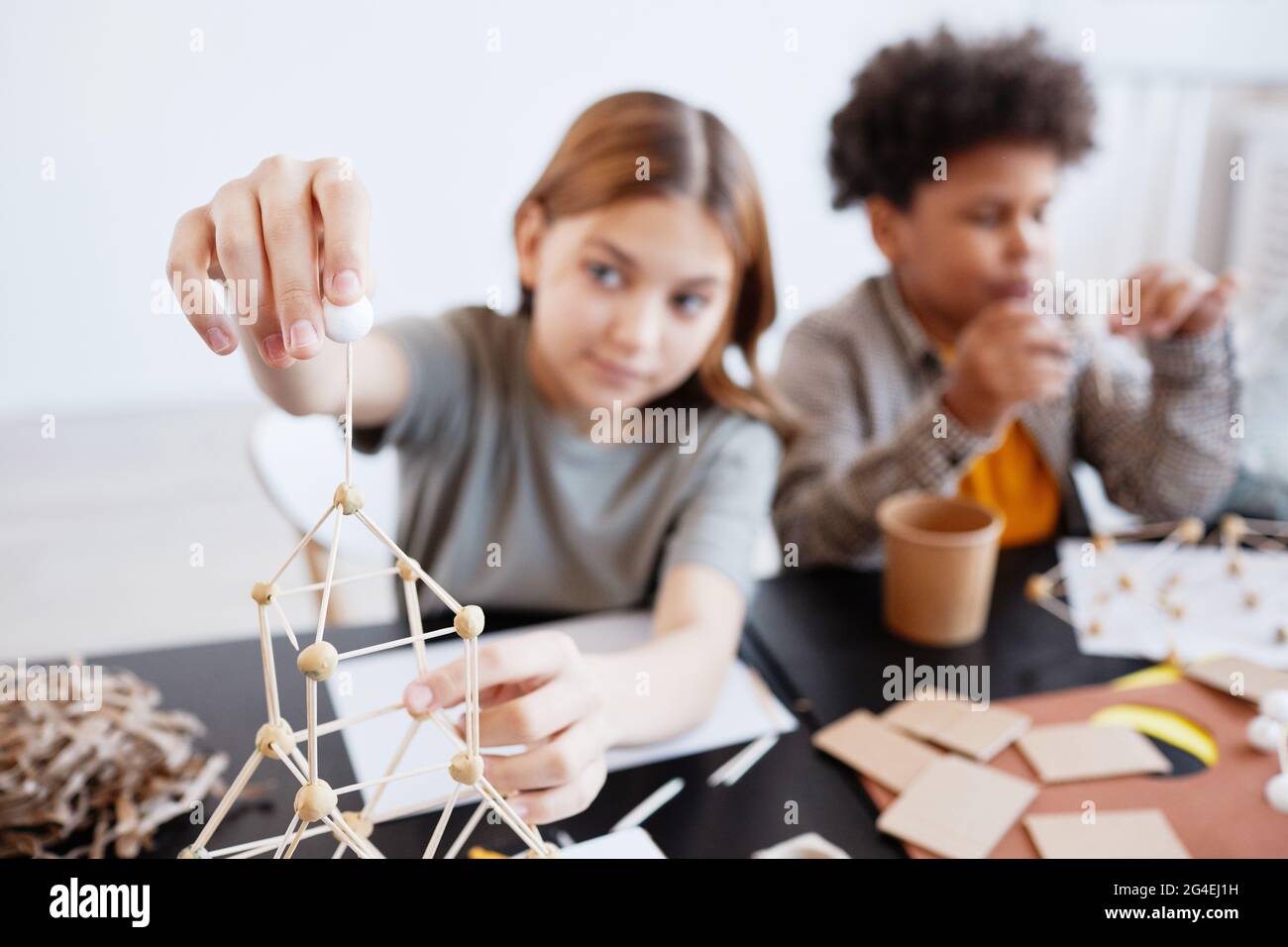 Portrait of teen girl making wooden models during art and craft class ...
