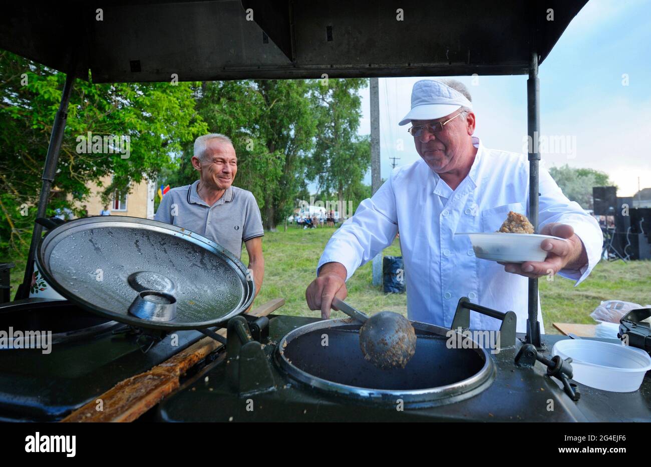 Cook standing in front of mobile field kitchen and putting free meal in ...