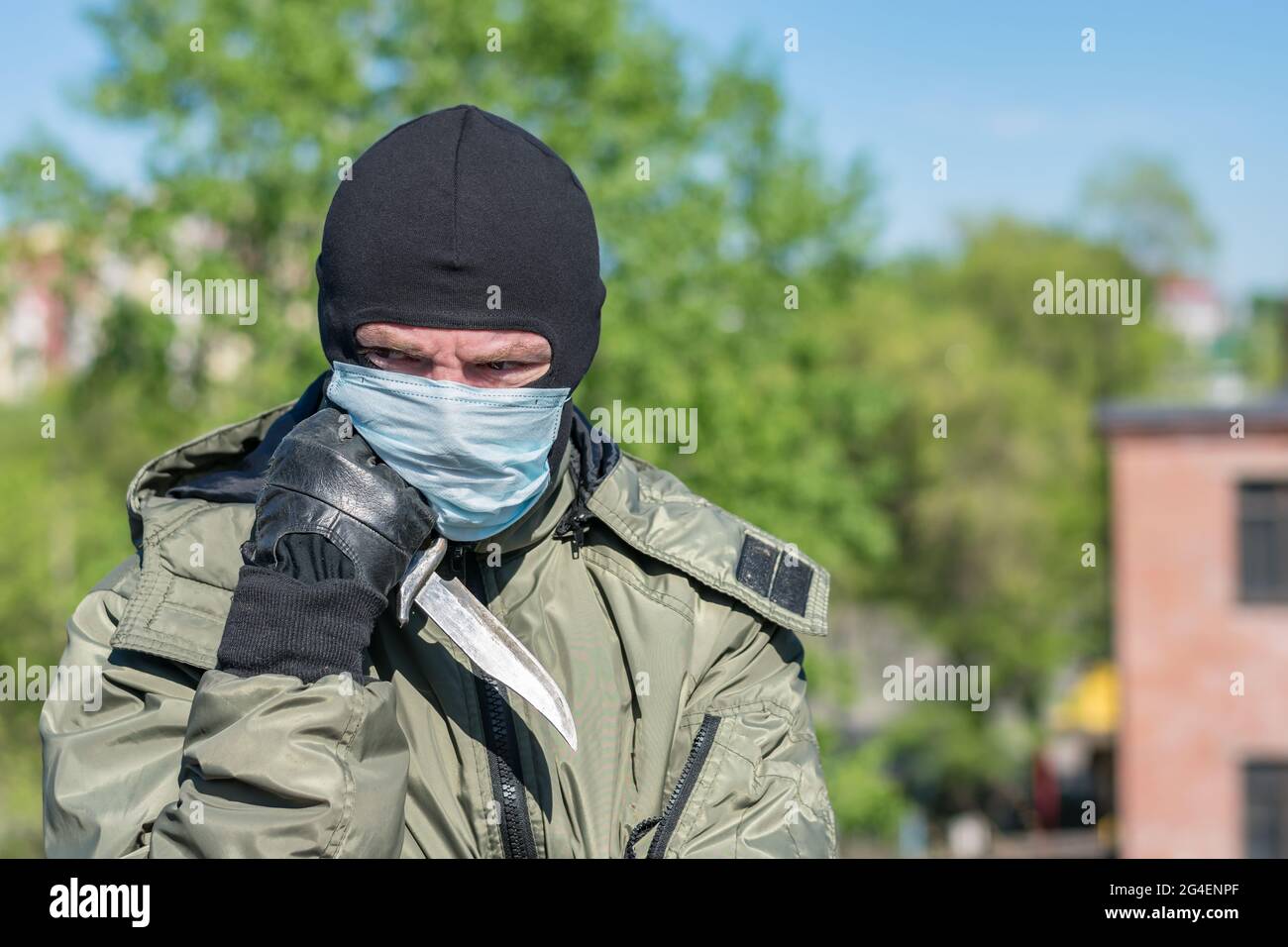 Portrait of a pensive army soldier in a balaclava and a medical mask ...