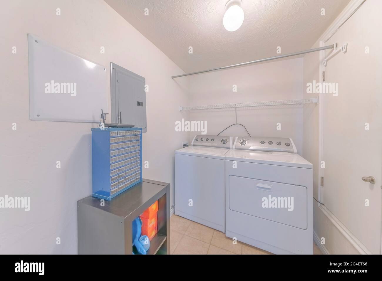 A laundry room with washing and drying machines, racks on the white ...