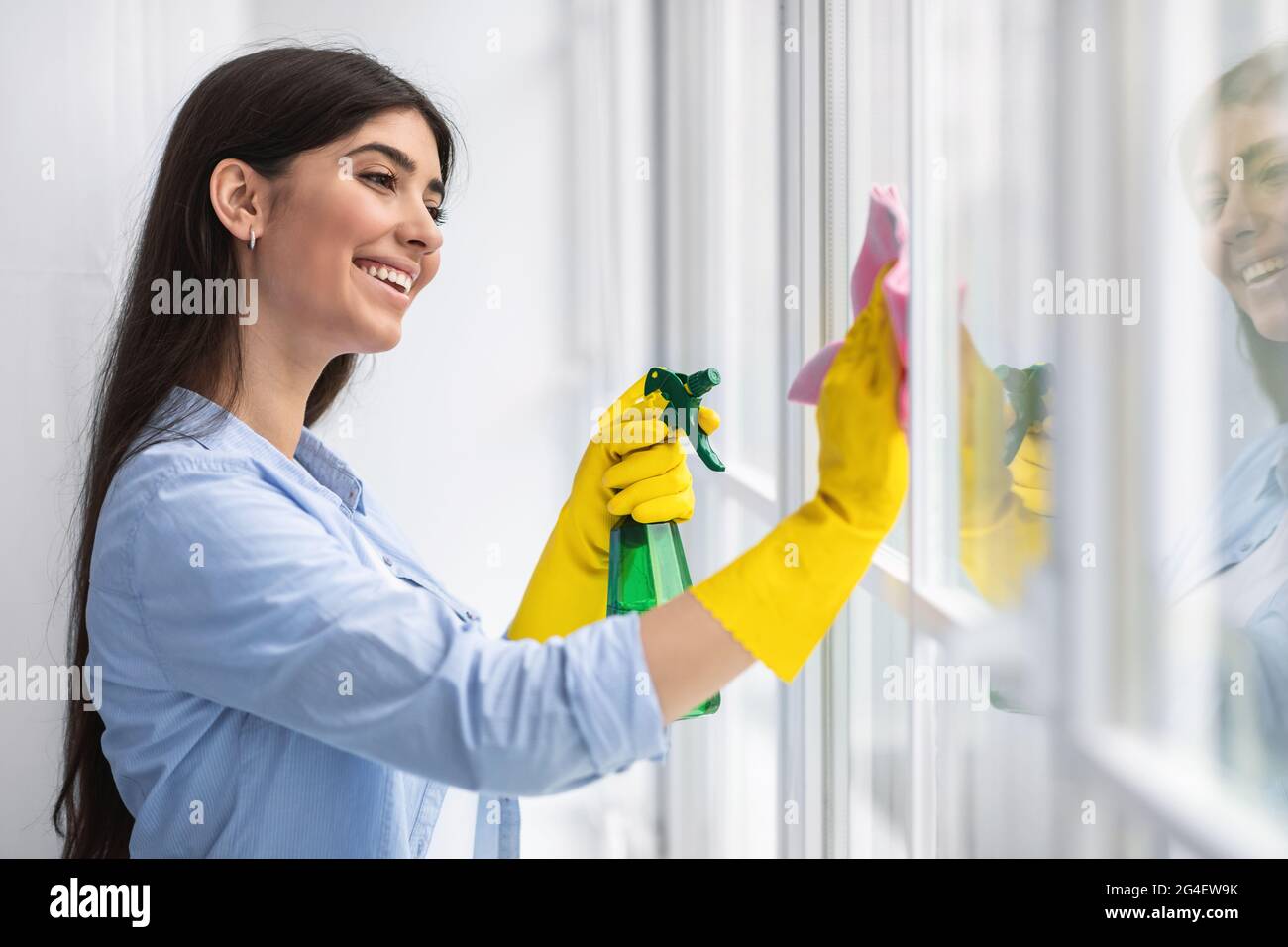 Woman cleaning window with rag and cleanser spray at home Stock Photo ...