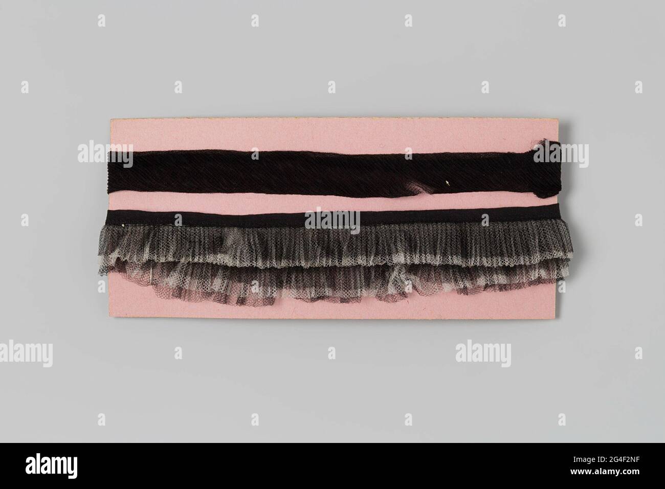 Two black ruffles injured to a rose piece of cardboard. Two black ...