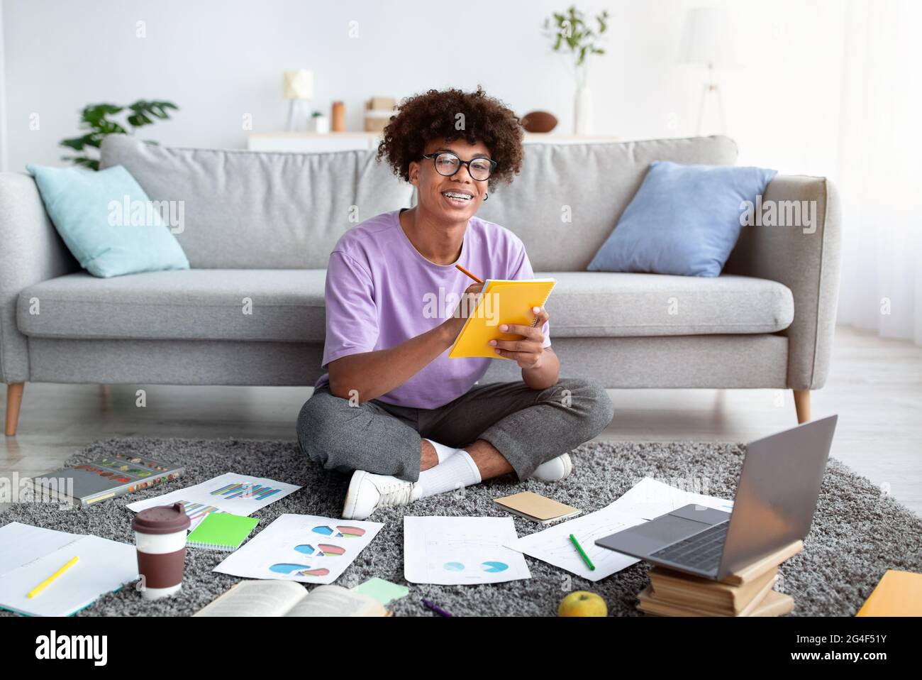 Remote education. Cool black teen guy taking notes during online class ...