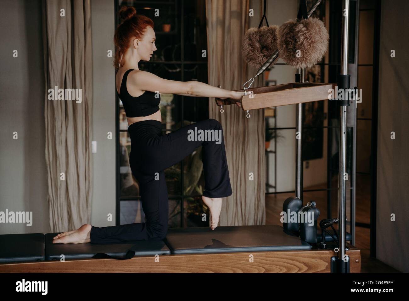 Slender fit pilates trainer showing stretching exercises on cadillac ...