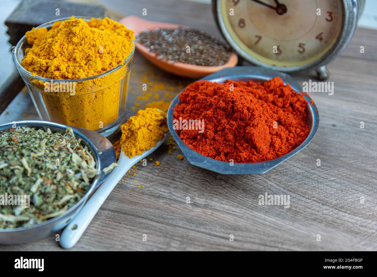 Colorful culinary spices and clock on wooden surface. Condiments used ...