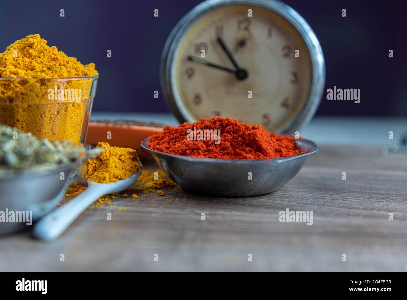 Colorful culinary spices and clock on wooden surface. Condiments used ...