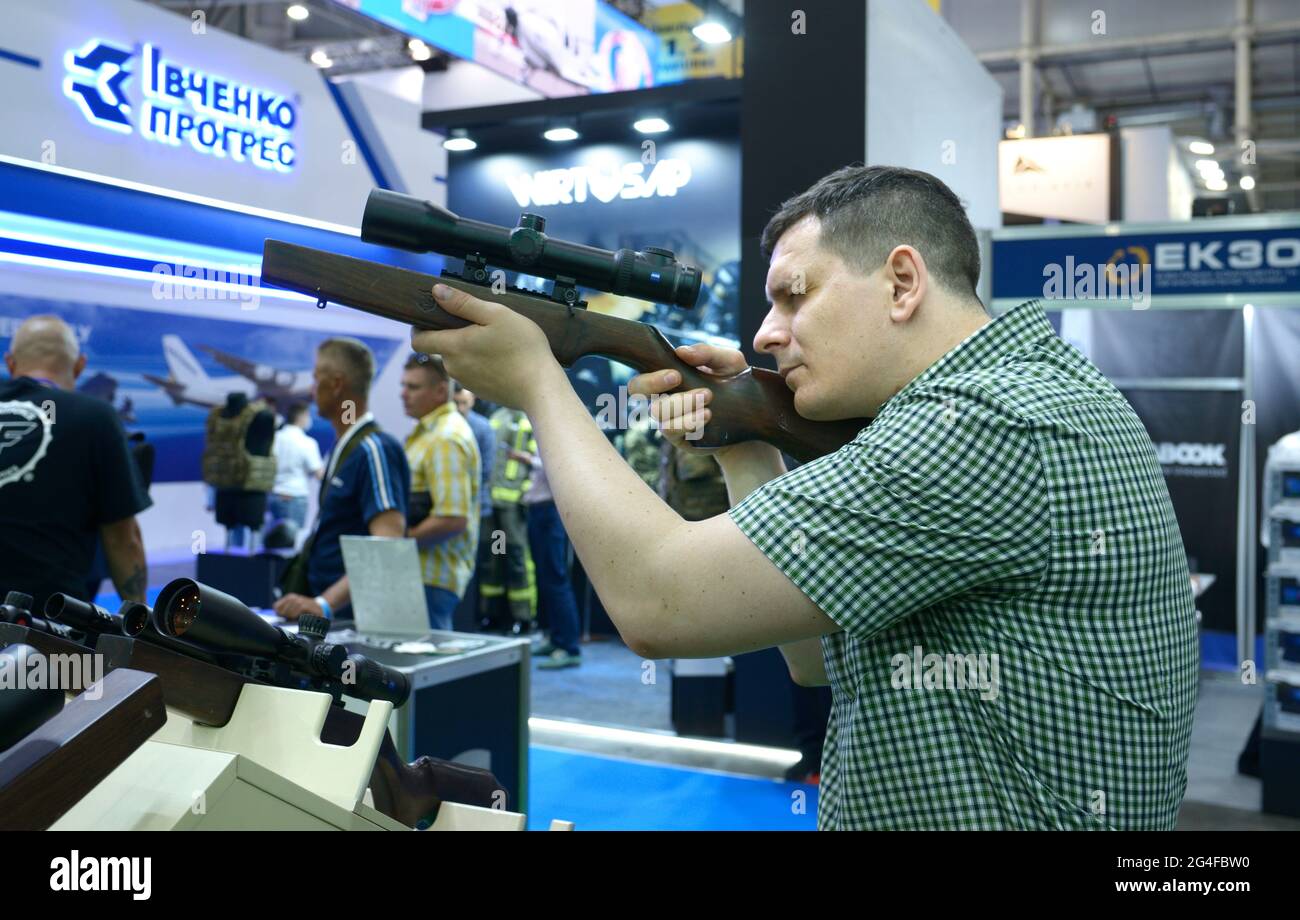 Young man looking through the telescopic sight of a rifle, gun shop ...