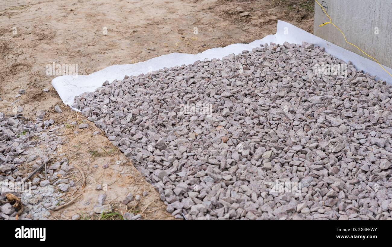 Construction crushed stone is poured and compacted on agrofibre before ...