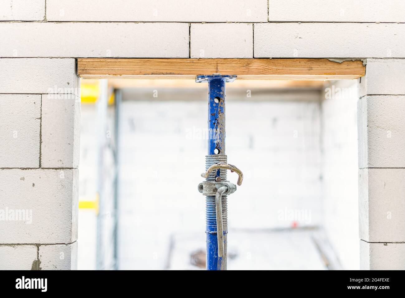 A construction jack supports a white cinder block wall in an unfinished ...