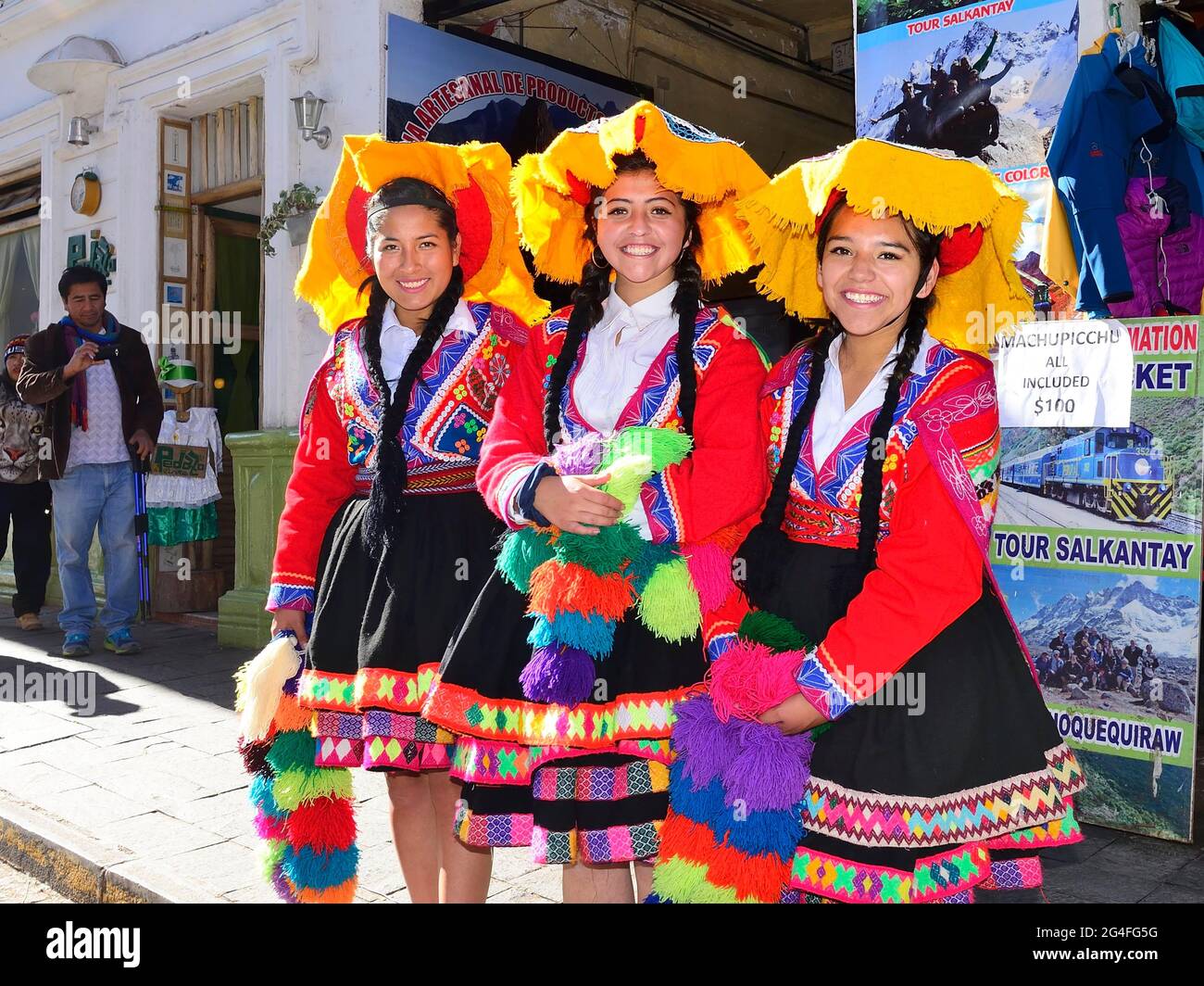Three young indigenous woman in colorful costumes in the old town ...