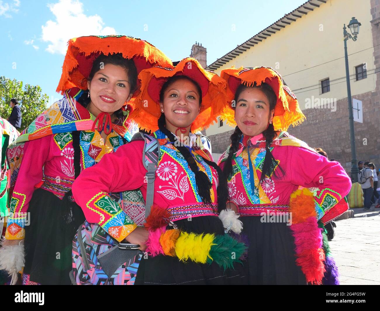 Three young indigenous woman in colorful costumes in the old town ...