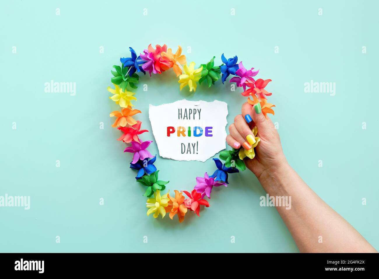Text Happy Pride Day on torn paper in rainbow heart from flower garland ...