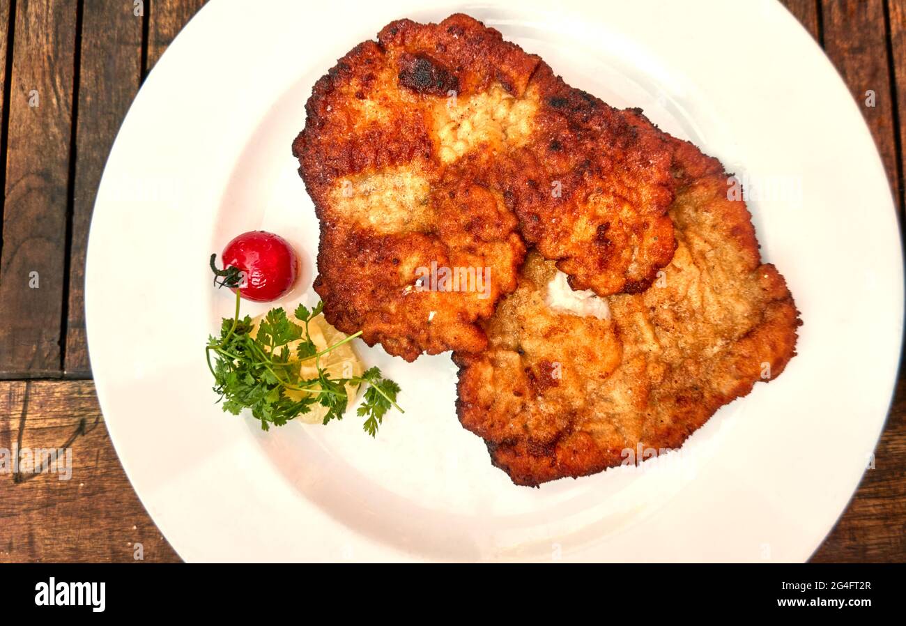 breaded pork schnitzel in the style of Austrian Wiener Schnitzel lies ...