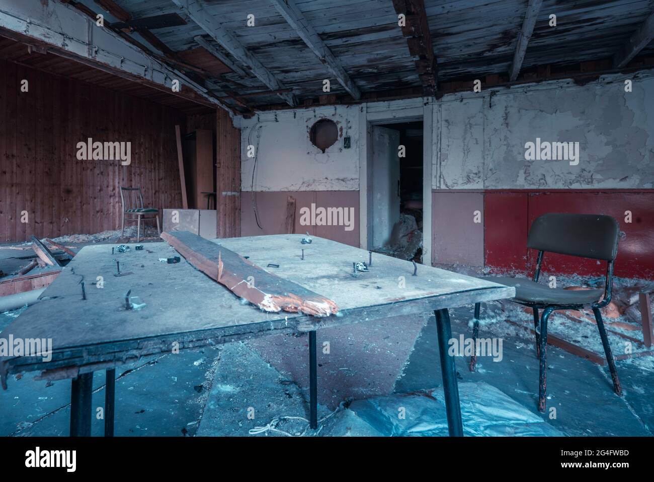 Dirty table with old nails in it and a chair in messy room of an old ...