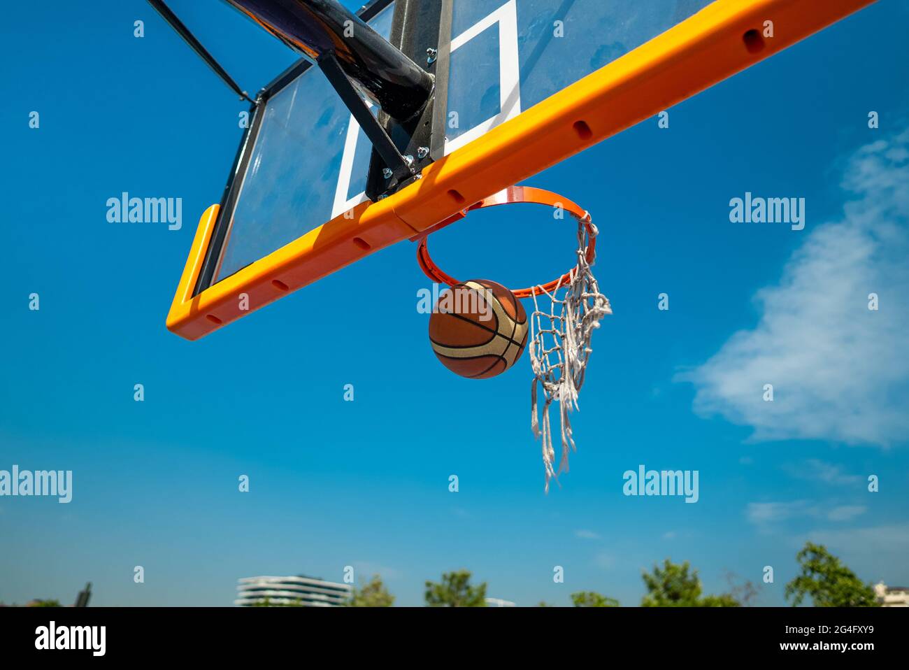 Basketball ball falling through old net. on playground Blue sky on ...