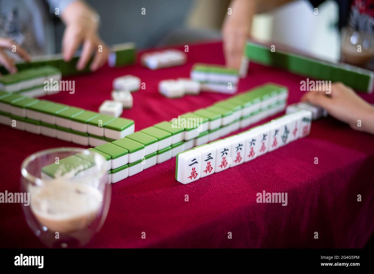 People playing mahjong traditional Chinese board game on a red table at ...