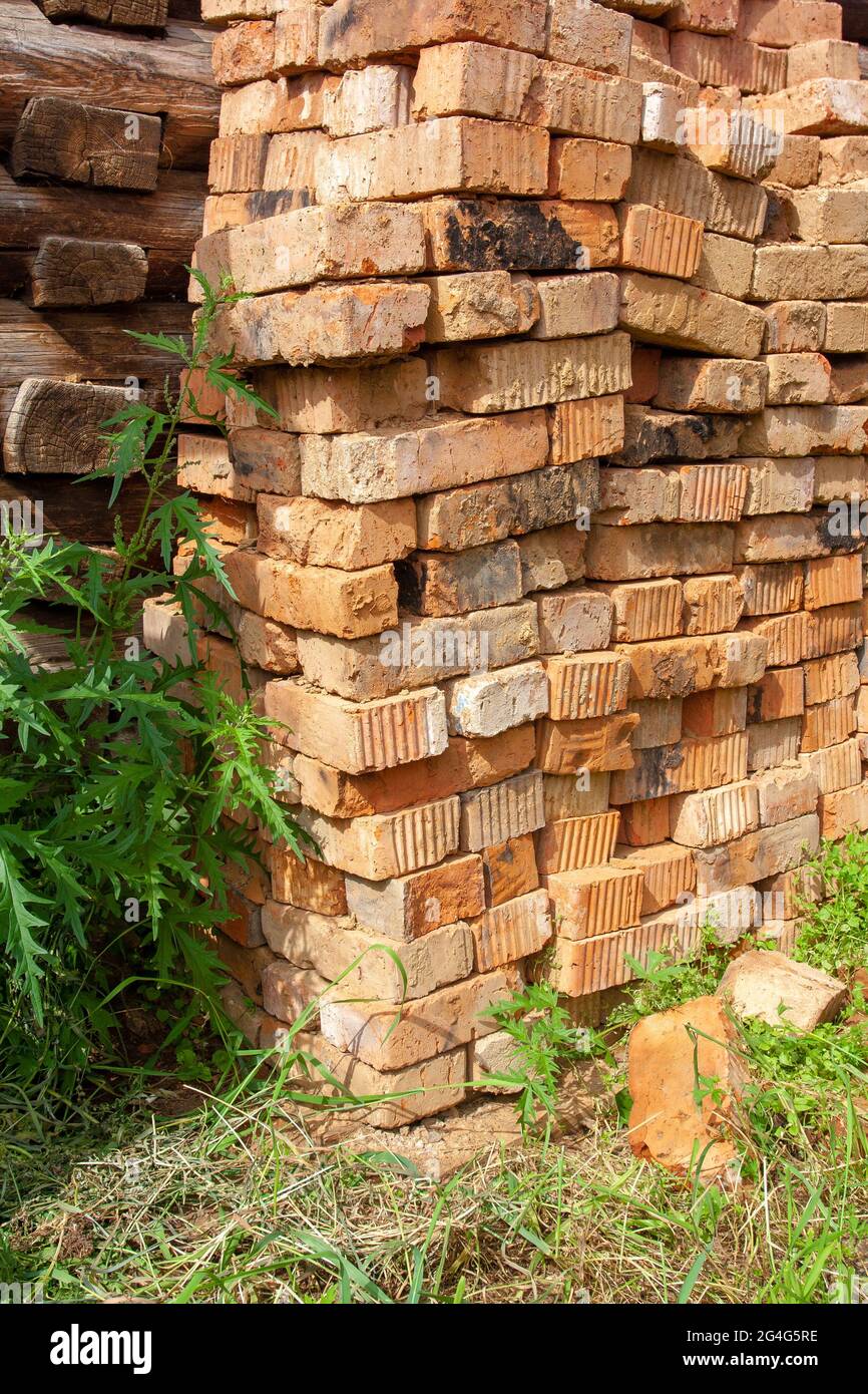 Pile of old bricks in the grass by the log wall. Vertical image Stock ...