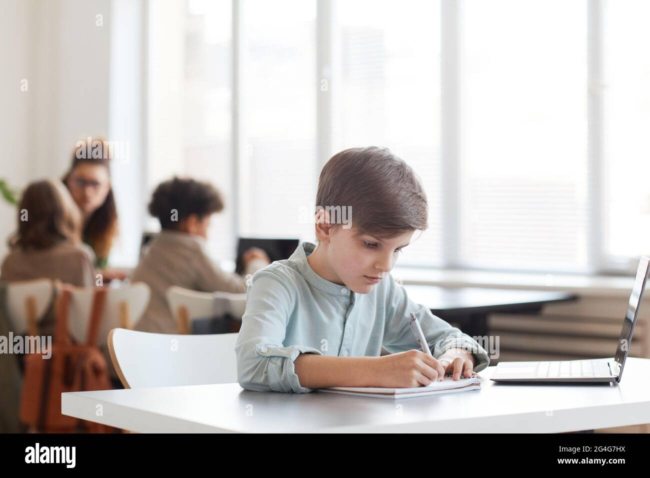 Portrait of cute boy reading book during class in school, copy space ...