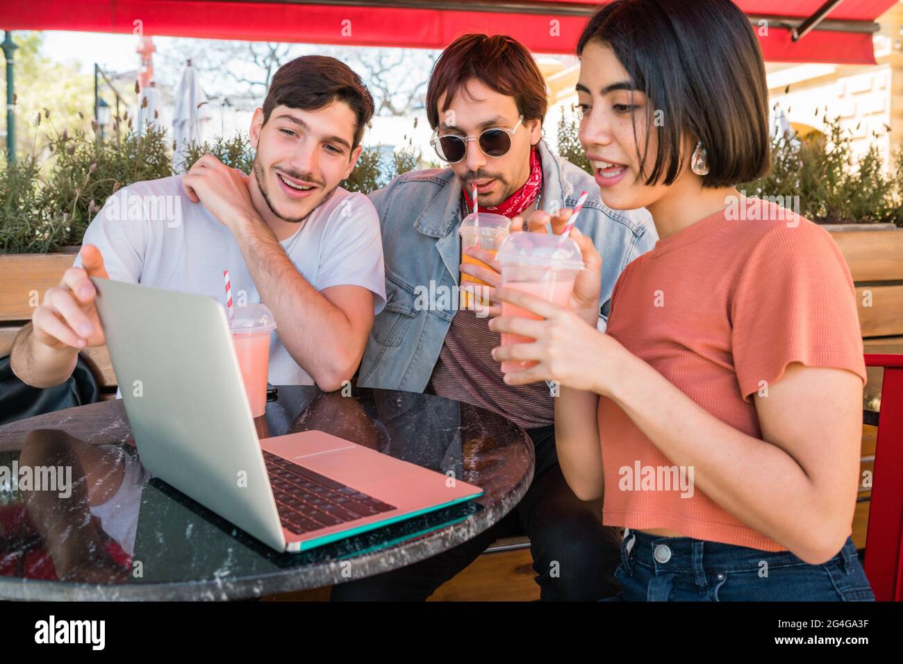 Three young friends using laptop at coffee shop Stock Photo - Alamy