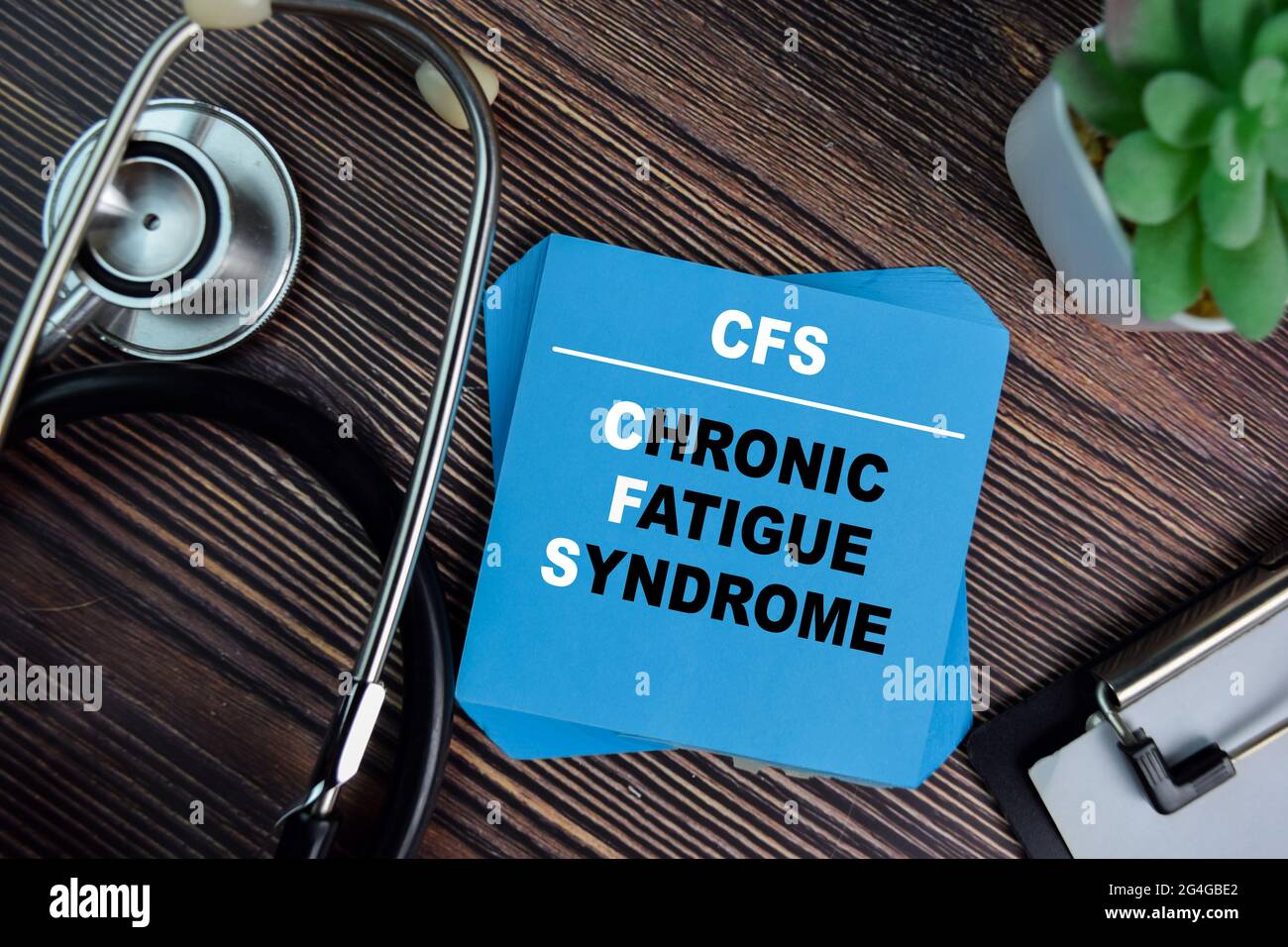 CFS - Chronic Fatigue Syndrome write on sticky notes isolated on Wooden ...