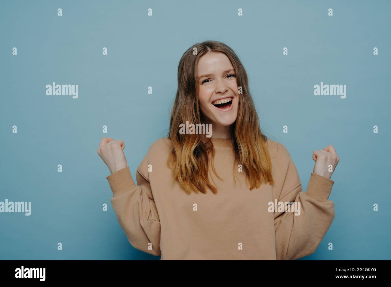 Teenage girl celebrating victory or success isolated on blue background ...