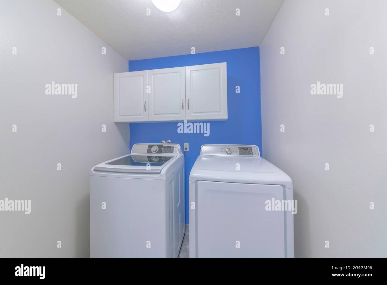 Laundry room with a washing machine, a dryer, and wooden cabinets for ...