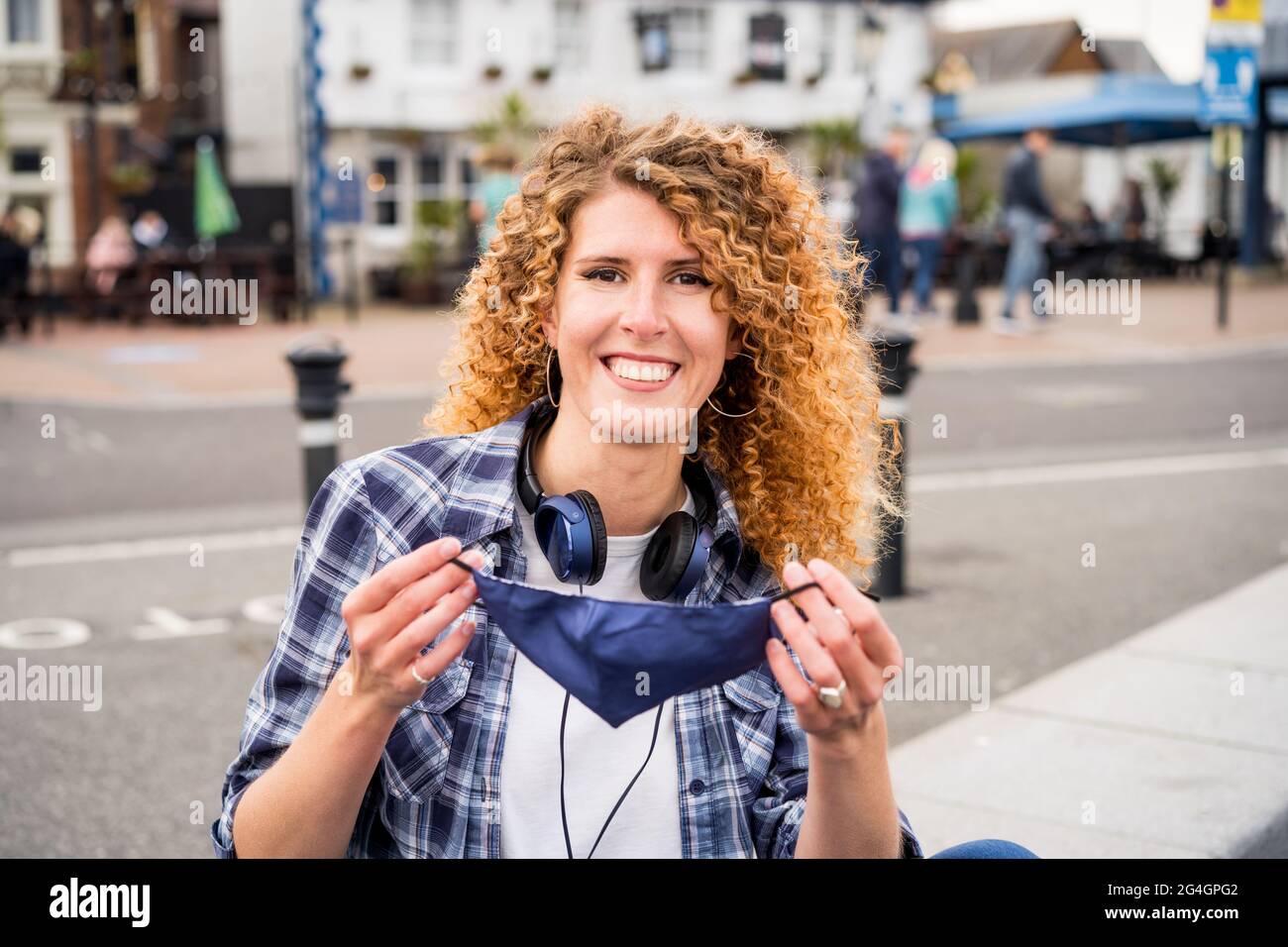 Young happy caucasian woman takes off a protective face-covering mask ...