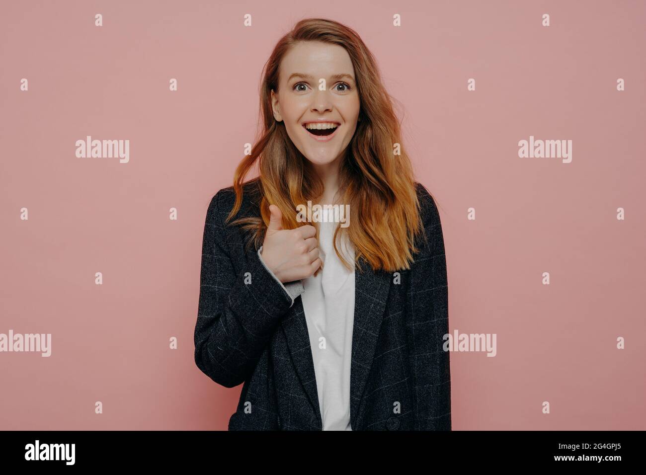 Surprised amazed young woman showing thumbs up Stock Photo - Alamy