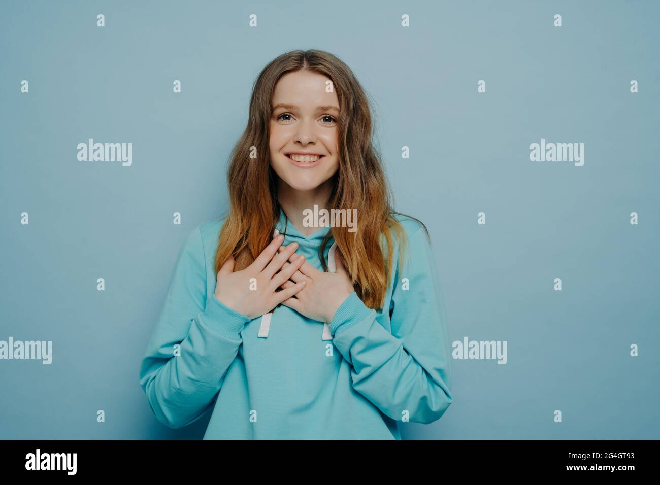Young woman holding hands on chest and expressing happiness and ...