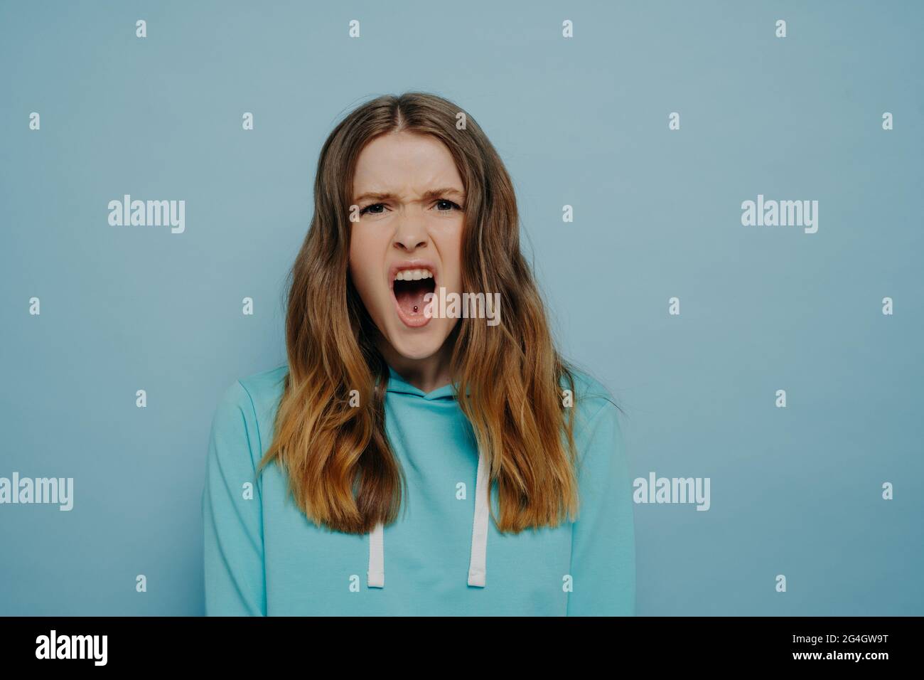 Pretty teenage girl expressing angry disbelief posing isolated over ...
