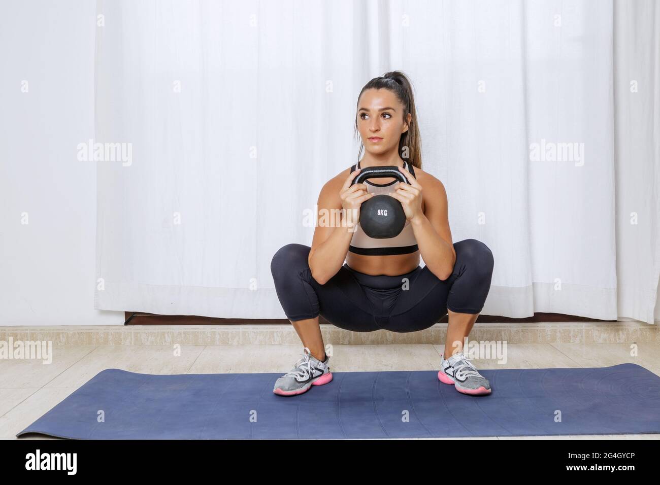 Full body of active young fit female in sportswear doing squats ...