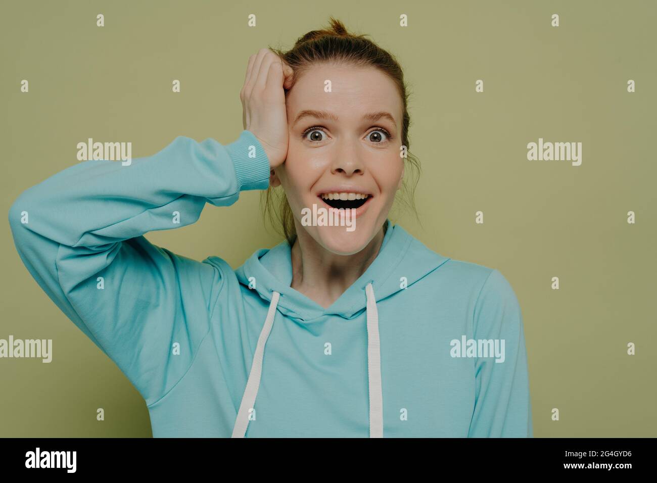 Excited young woman expressing shock holding hand at head Stock Photo ...