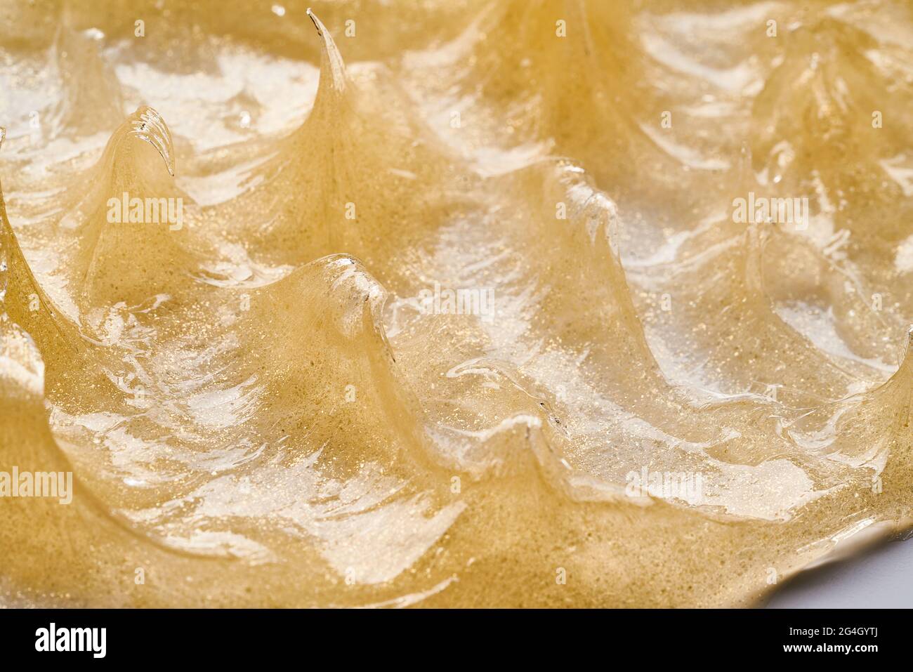 Transparent smear and texture of golden cosmetic gel on a white ...