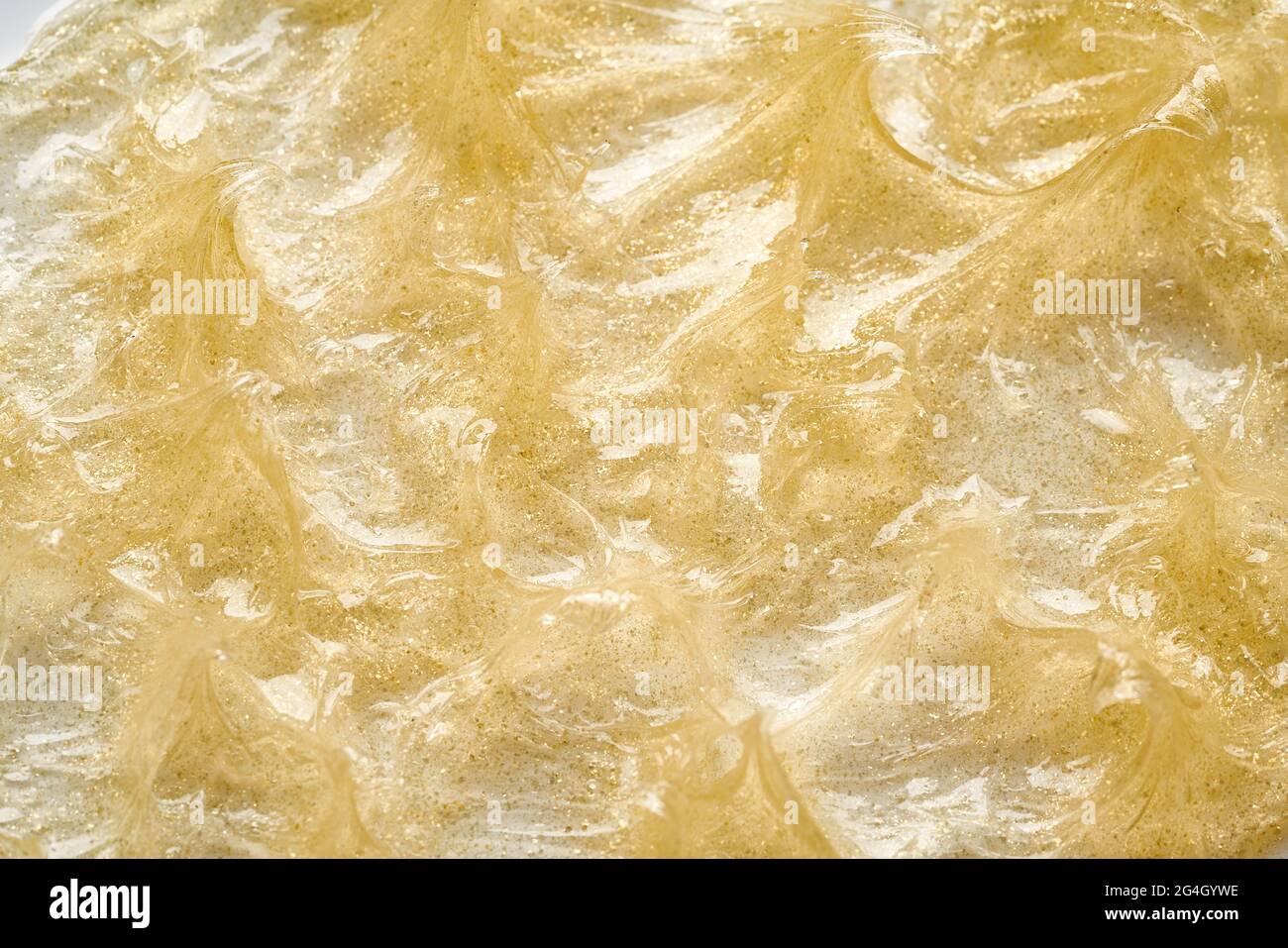 Transparent smear and texture of golden cosmetic gel on a white ...