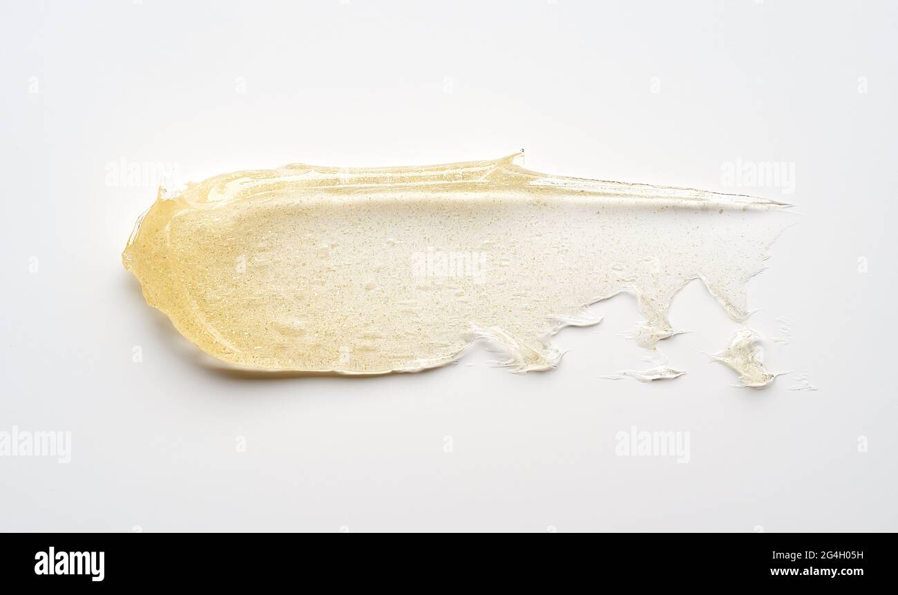 Transparent smear and texture of golden cosmetic gel on a white ...