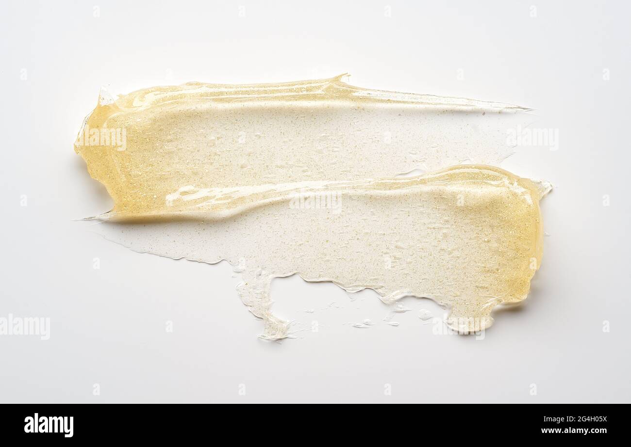 Transparent smear and texture of golden cosmetic gel on a white ...
