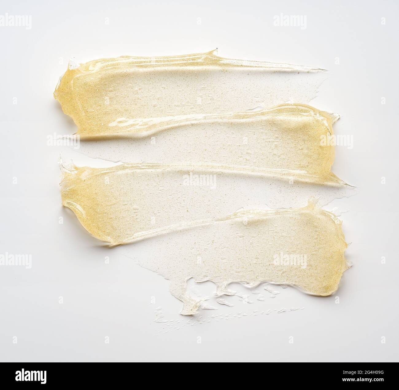Transparent smear and texture of golden cosmetic gel on a white ...