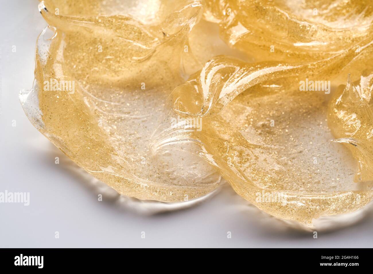 Transparent smear and texture of golden cosmetic gel on a white ...