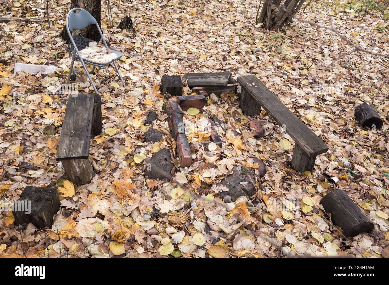 Abandoned wooden benches stand around an empty bonfire, autumn park ...
