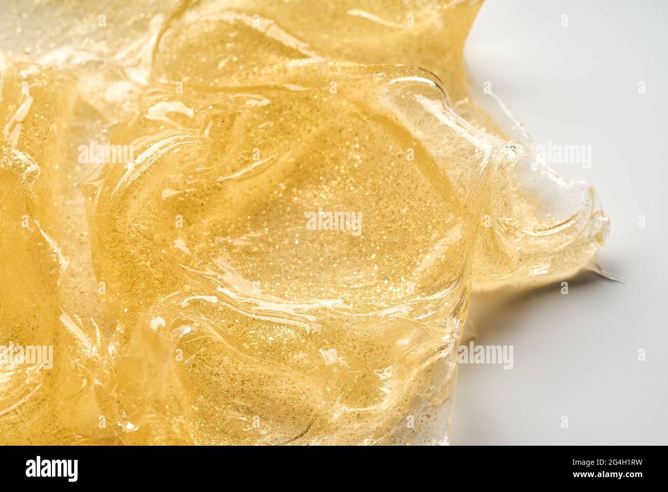 Transparent smear and texture of golden cosmetic gel on a white ...
