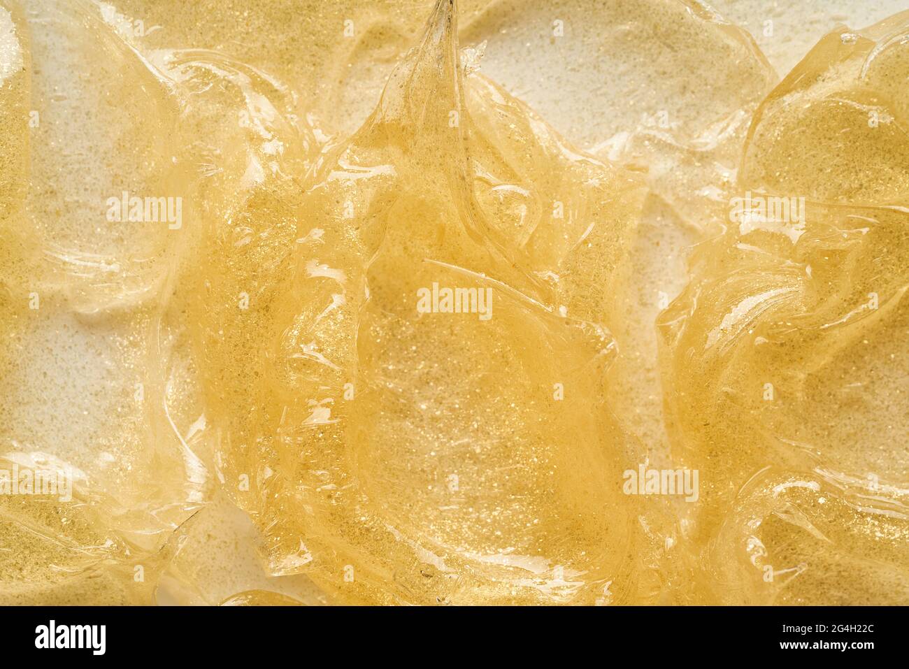 Transparent smear and texture of golden cosmetic gel on a white ...