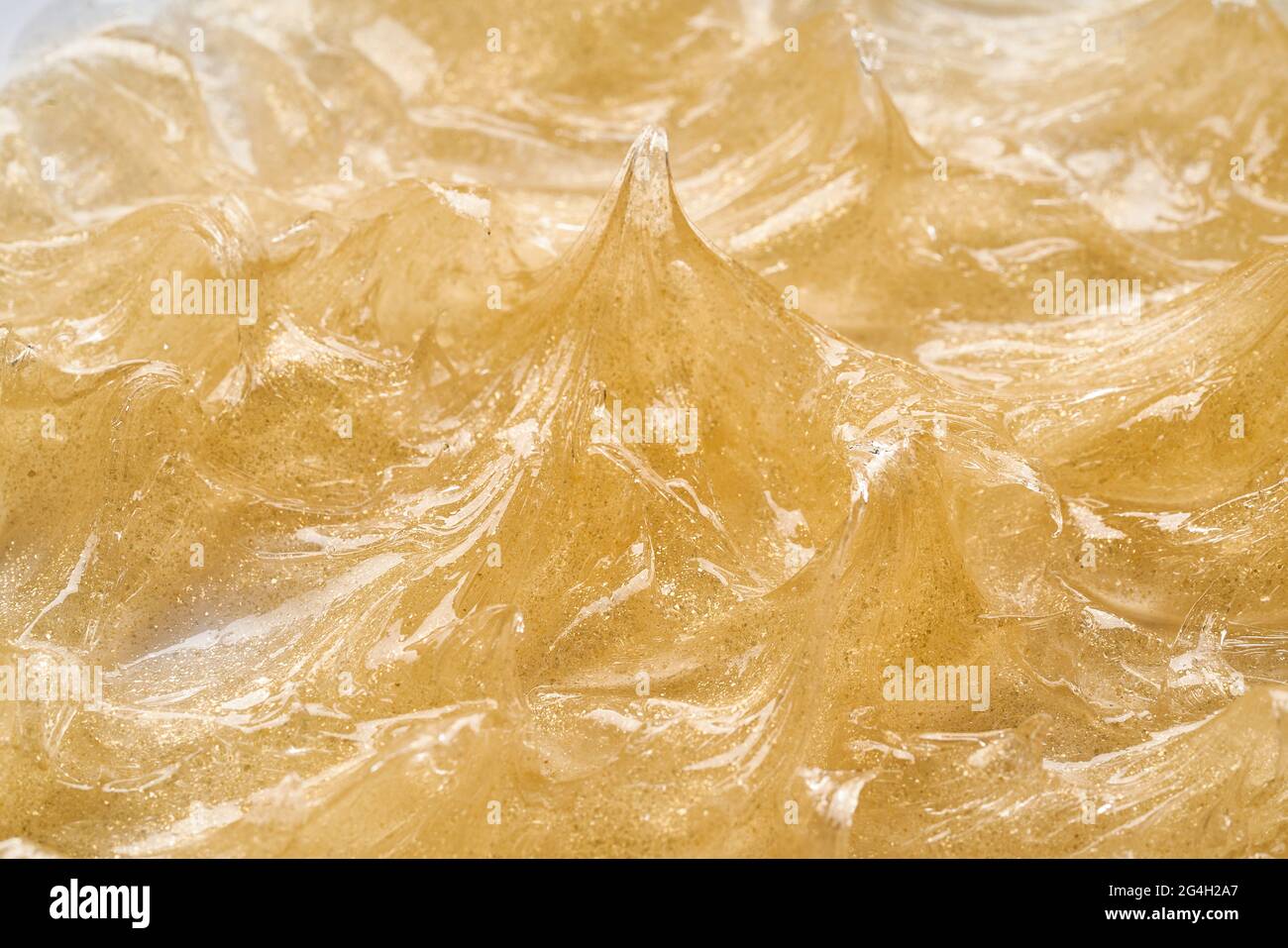 Transparent smear and texture of golden cosmetic gel on a white ...